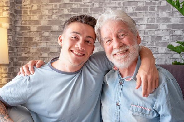 Portrait of a young boy and his old grandfather smiling looking at ...