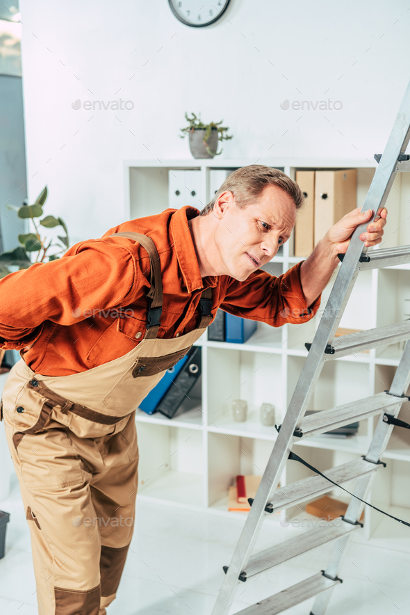 repairman standing and holding on ladder and back in office Stock Photo ...