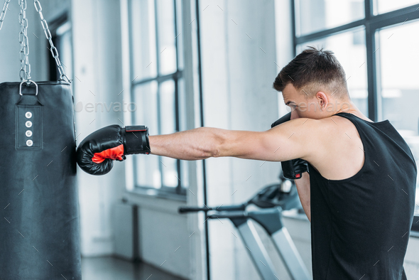 side view of muscular young man boxing with punching bag in gym Stock ...