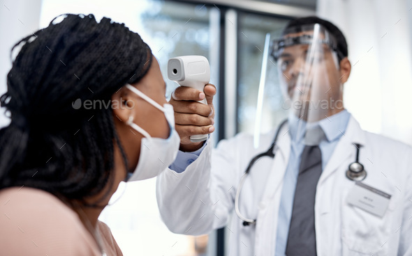 Shot of a doctor taking a patients temperature with an infrared ...