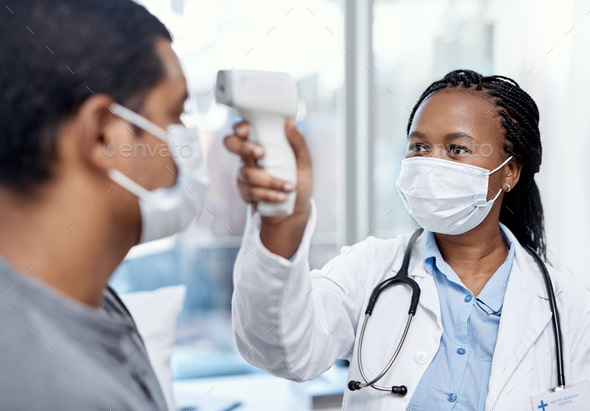 Shot of a doctor taking a patients temperature with an infrared ...