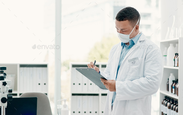 Shot of a young scientist writing notes on a clipboard in a laboratory ...