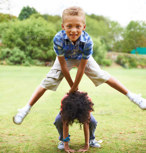 Leapfrogging. A young boy doing a leapfrog over his friends back. Stock ...