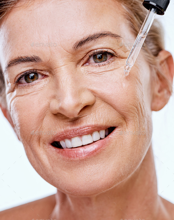 Shot of a mature woman posing with a serum dropper against her face ...