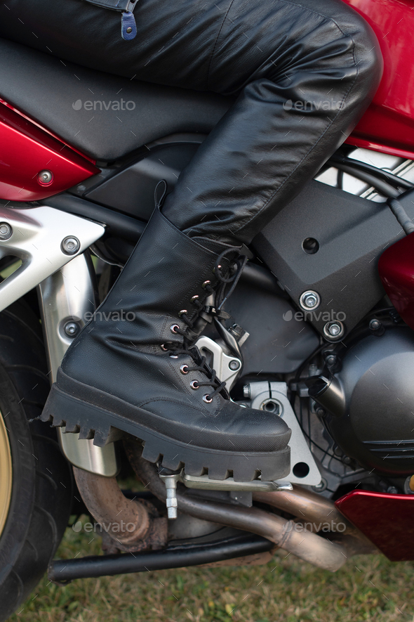 girls feet on the steps of a Honda motorcycle in a beautiful black boot ...