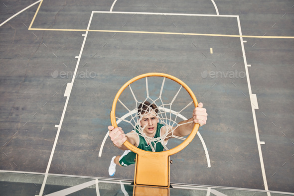 Portrait of basketball player hanging on hoop on a basketball court ...