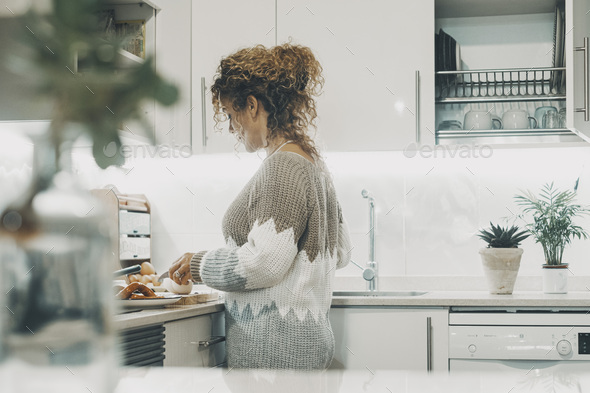 Side real view of woman cooking at home in the white minimal modern ...