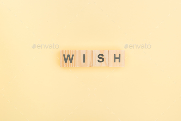 top view of wish lettering made of wooden blocks on yellow background ...