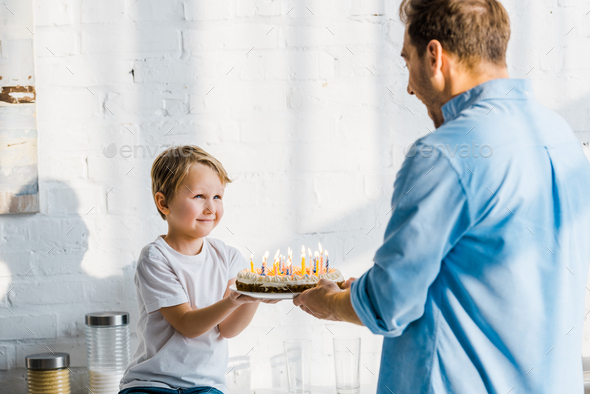 father giving birthday cake to adorable preschooler son in kitchen ...