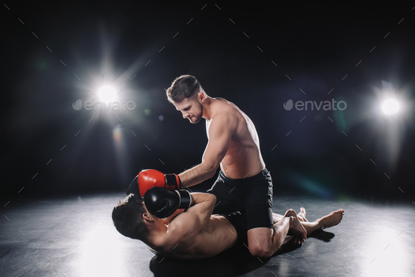strong mma fighter in boxing gloves sitting on opponent and punching ...
