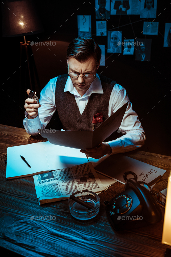 High angle view of concentrated detective in glasses reading dossier in ...