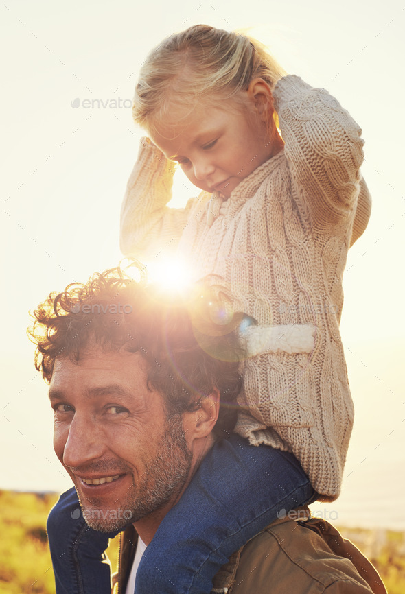 Shot of a father carrying his little girl on his shoulders while walking outdoors Stock Photo by ...