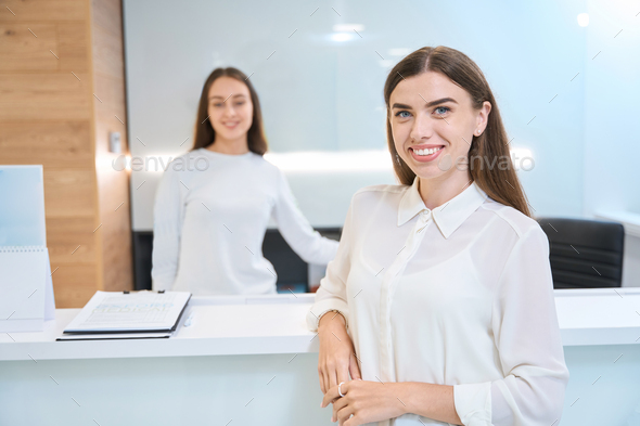Joyous customer and secretary at reception desk Stock Photo by Iakobchuk