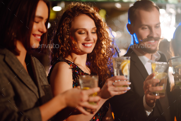 Cheering and drinking cocktails. Group of friends partying in nightclub ...