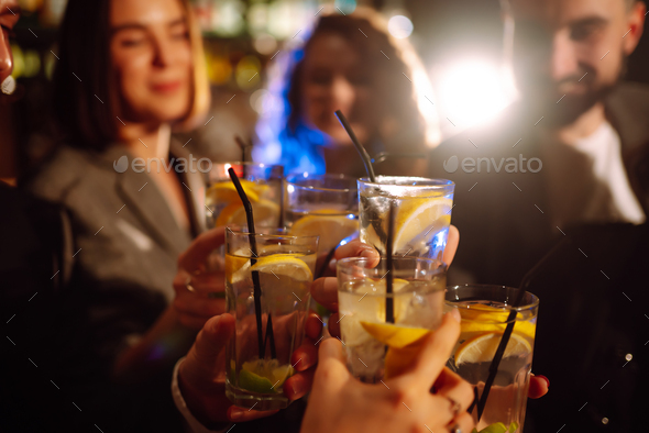 Cheering and drinking cocktails. Group of friends partying in nightclub ...