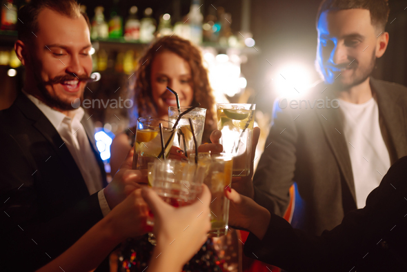 Cheering and drinking cocktails. Group of friends partying in nightclub ...