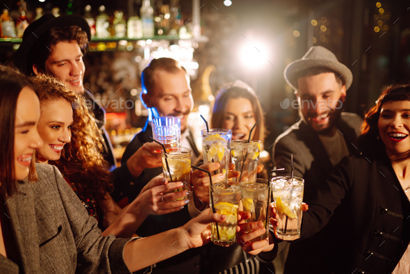 Cheering and drinking cocktails. Group of friends partying in nightclub ...