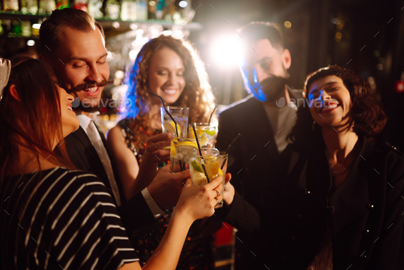 Cheering and drinking cocktails. Group of friends partying in nightclub ...