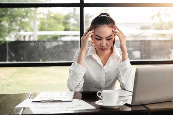 Asian businesswoman are serious at work causing headache stressed out ...
