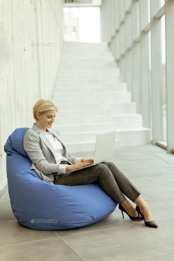 Businesswoman using laptop computer on lazy bag in the modern office ...