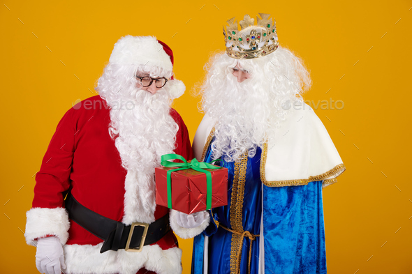 Santa Claus and the Wise Man together looking at a Christmas present ...
