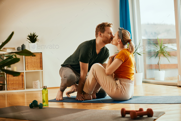 Athletic couple kissing while exercising together at home. Stock Photo ...