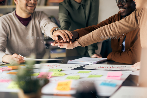 Close up of creative business team gathering hands in unity while ...