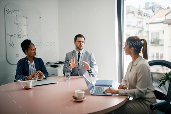 Male CEO communicating with colleagues during business meeting in the ...