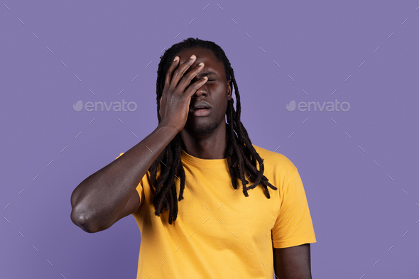 Tired upset black guy touching face over purple studio background Stock ...