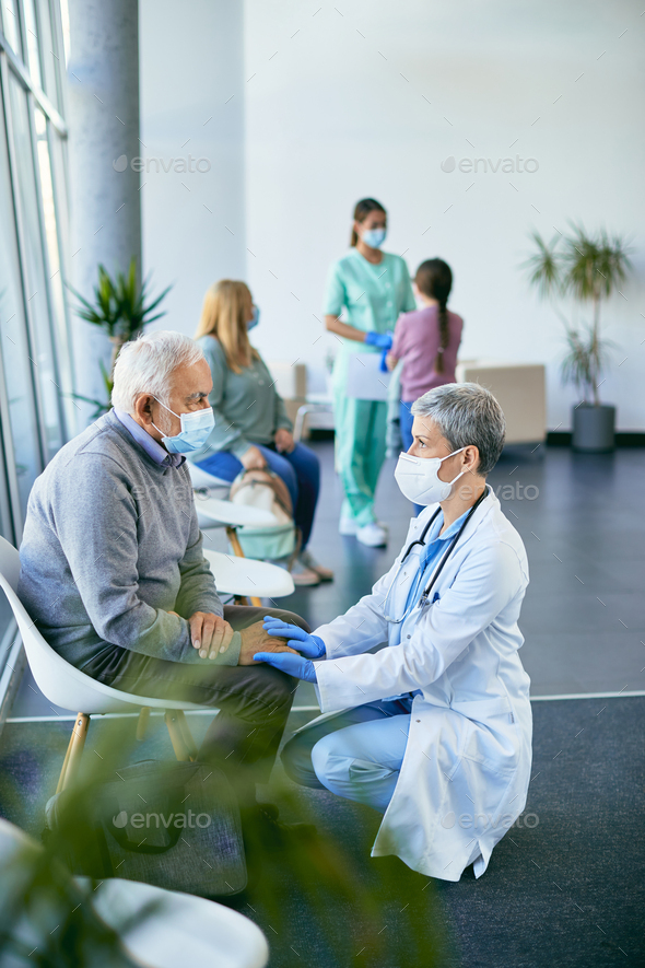 Caring doctor holding hands with her senior patient while talking to ...