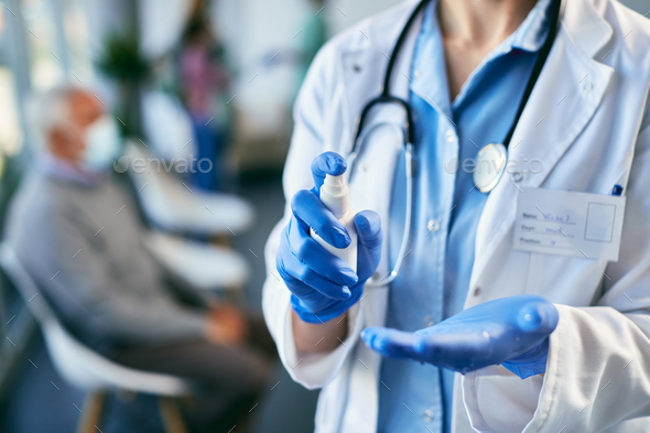 Close-up of doctor spraying her hands with disinfectant while working ...