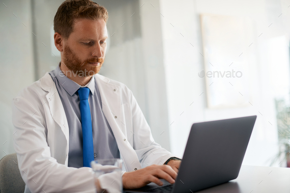 General practitioner using laptop while working at doctor's office ...