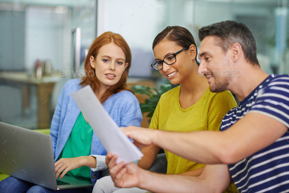Weve got this. Three co-workers looking over some work documents in the ...
