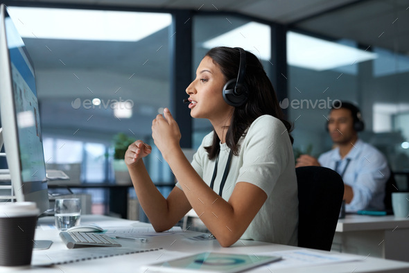 Shot of a young woman using a headset and computer in a modern office ...