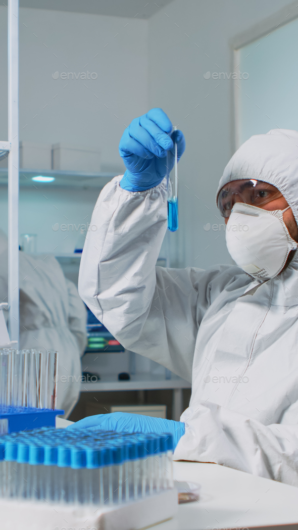 Biologist doctor in ppe suit checking liquid sample typing on pc Stock ...
