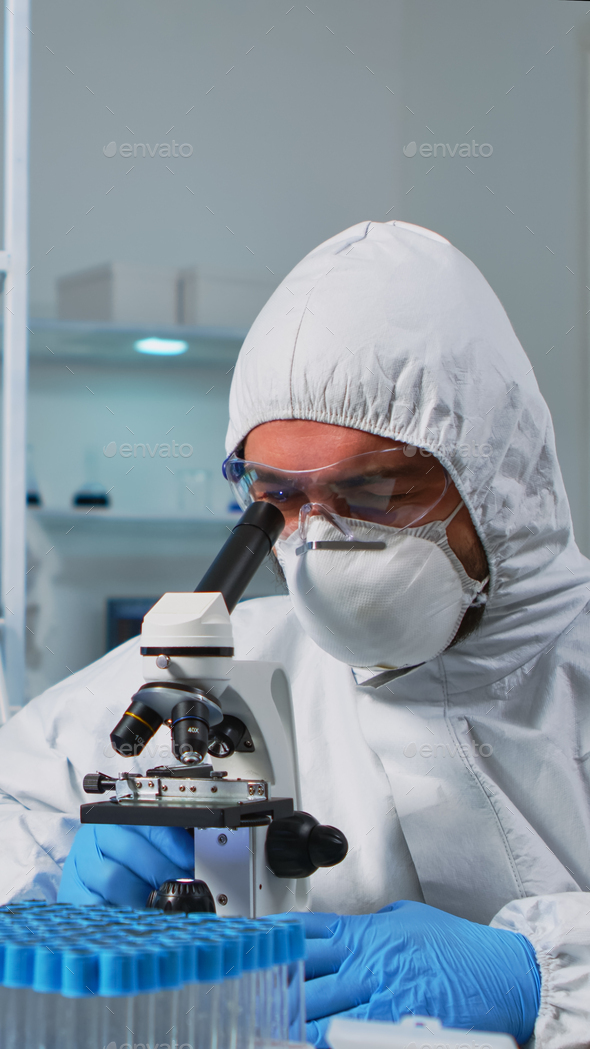 Biologist doctor in coverall checking DNA sample using microscope Stock ...