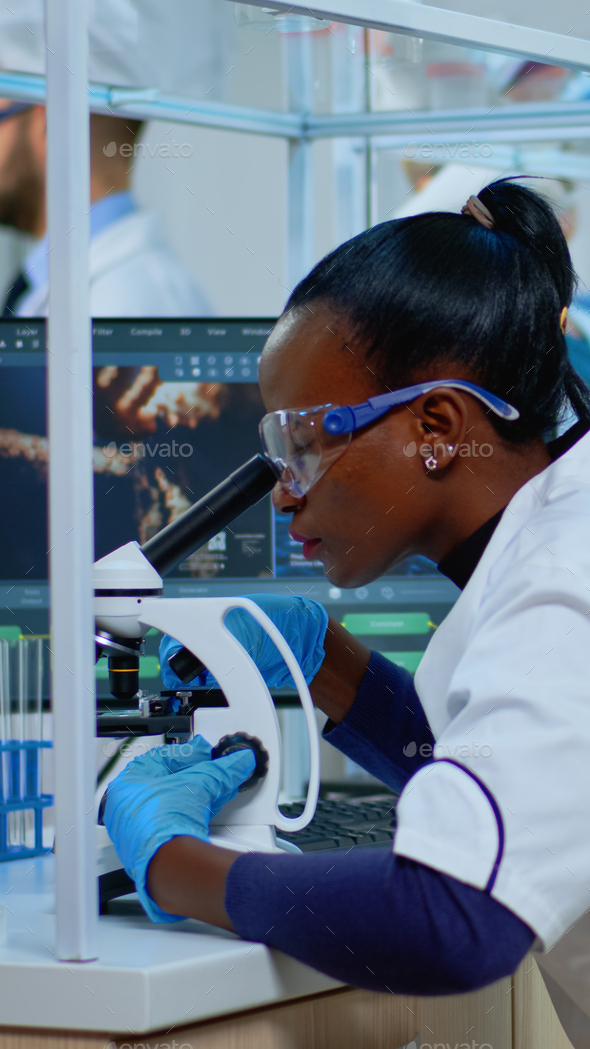 Black woman chemist analysing reaction of virus on microscope Stock ...