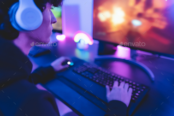 Young gamer having fun playing online video games with computer at home ...