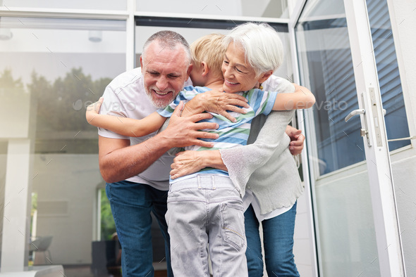 Senior grandparents hugging their small grandson at home. Little boy ...