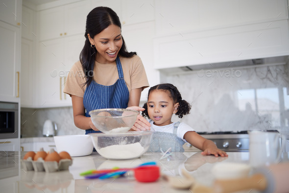 Caring single mother and small adorable daughter baking together in a ...