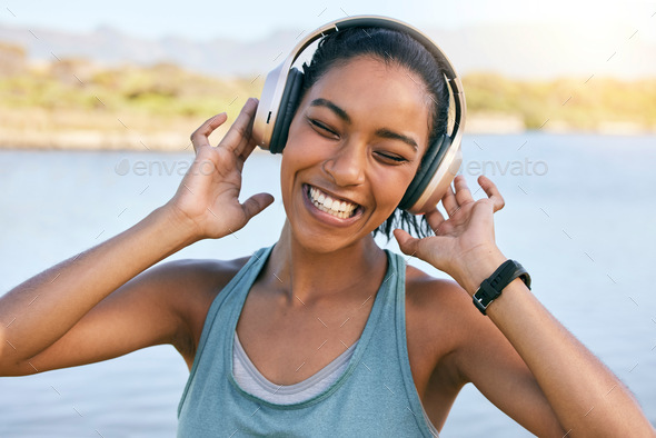 Excited woman smiling and listening to music while out on a lake. Happy ...
