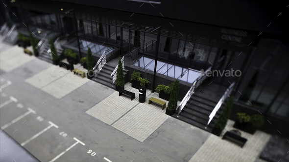 Parking entrance to office building with parking and benches. Facade of ...