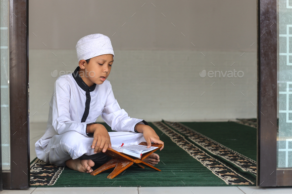 Muslim kid boy reciting koran or Qur'an Stock Photo by Queenmoonlite35