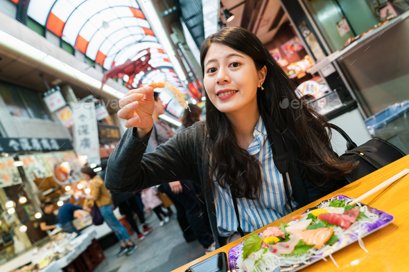 girl showing sashimi with hand at kuromon ichiba Stock Photo by ...