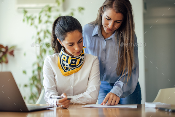 Concentrated adult woman, receiving help at work. Stock Photo by bnenin