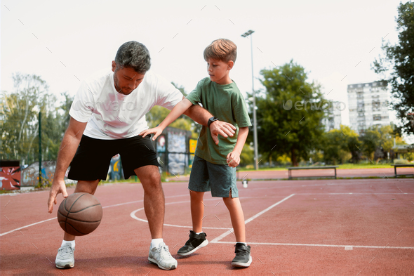 Father and son at public basketball court playing basketball. Stock ...