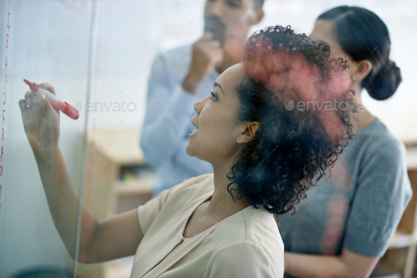 Shot of a group of creative businesspeople plotting out details on a ...