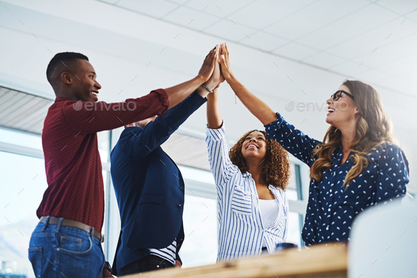Cropped shot of a group of creative employees high fiving while ...