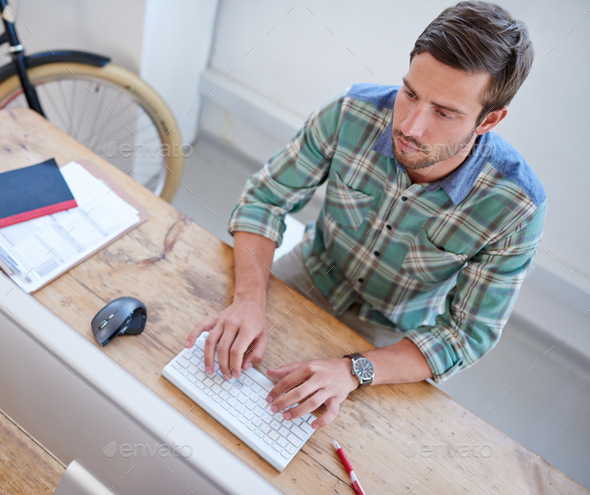 Top view of a handsome young man typing on his wireless keyboard at his ...