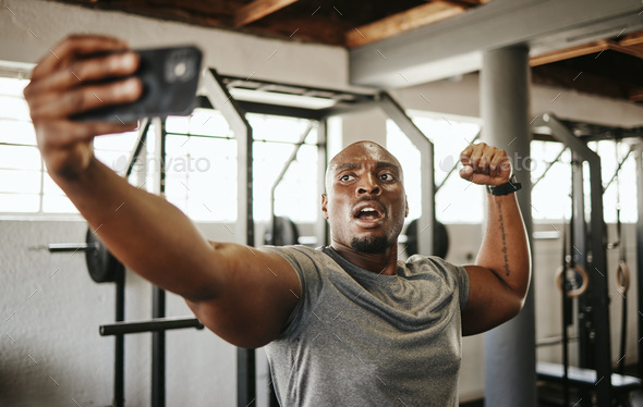 Gym selfie, smartphone and man flexing arm muscle for a post gyming ...